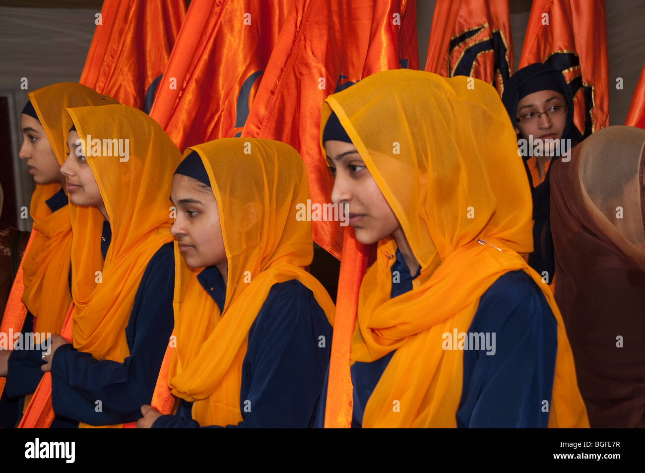 Young Sikh women in blue tunics and saffron scarves carrying Nisan ...