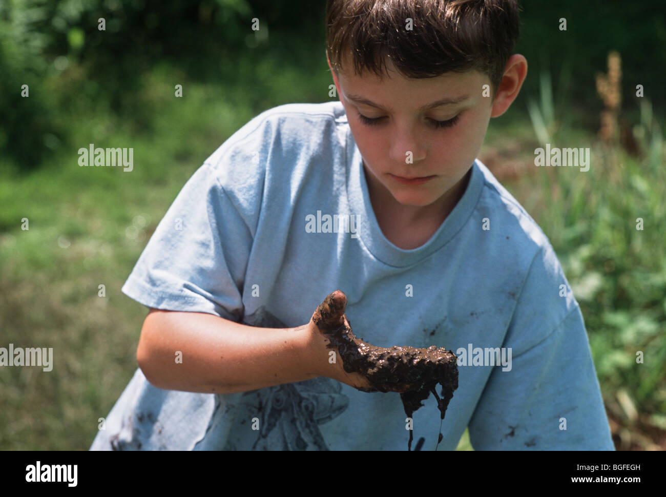8 year-old child examines creatures in mud at Watershed Pond ...