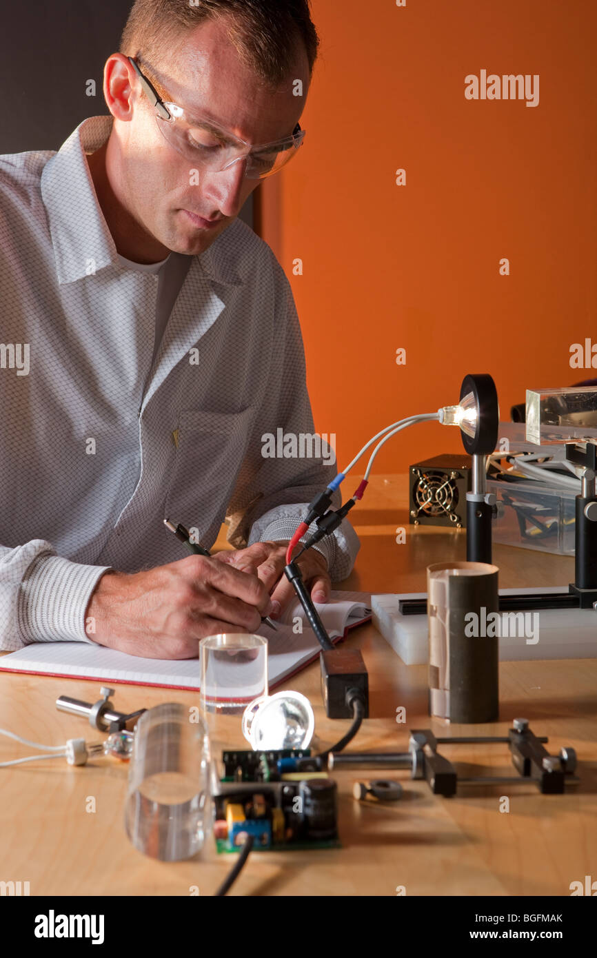 A researcher in a lab coat making notes on an experiment Stock Photo ...