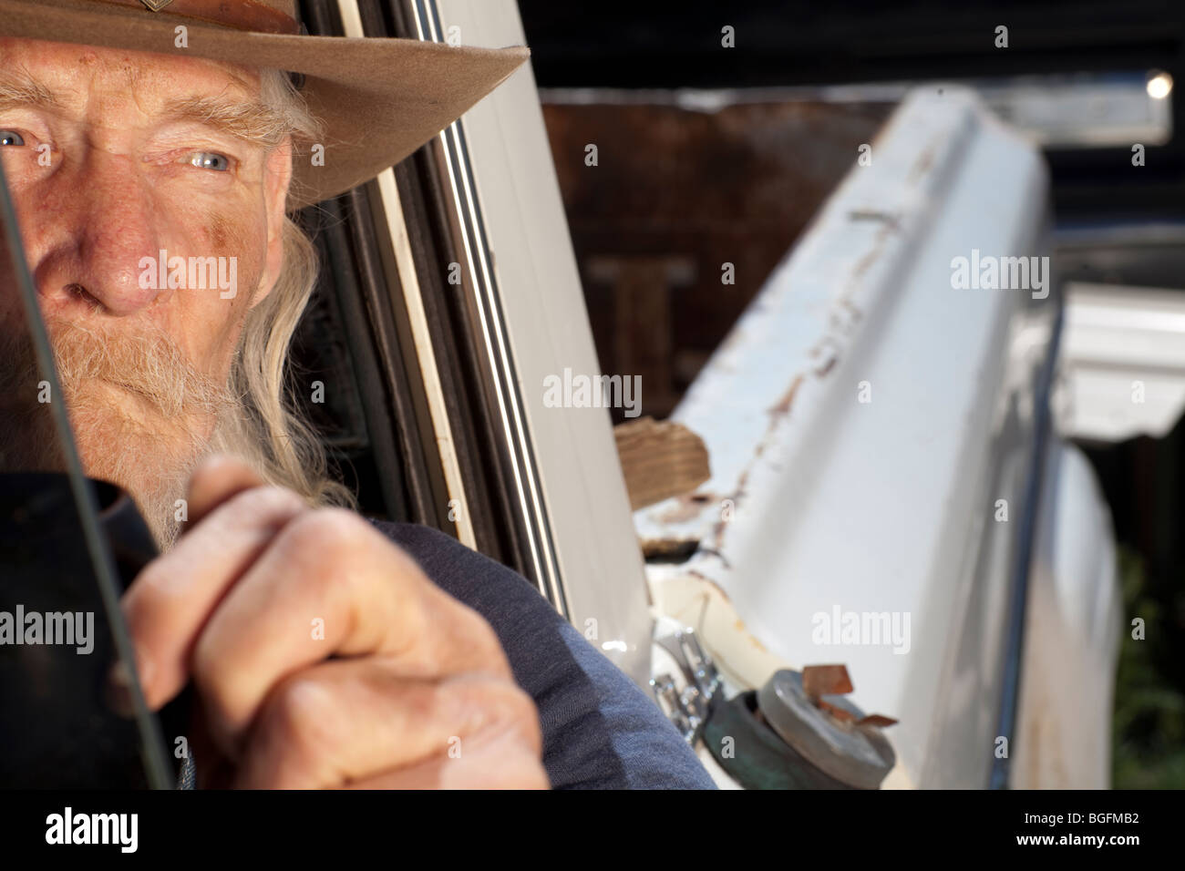 An elderly man with a white beard driving a pickup truck and staring ...
