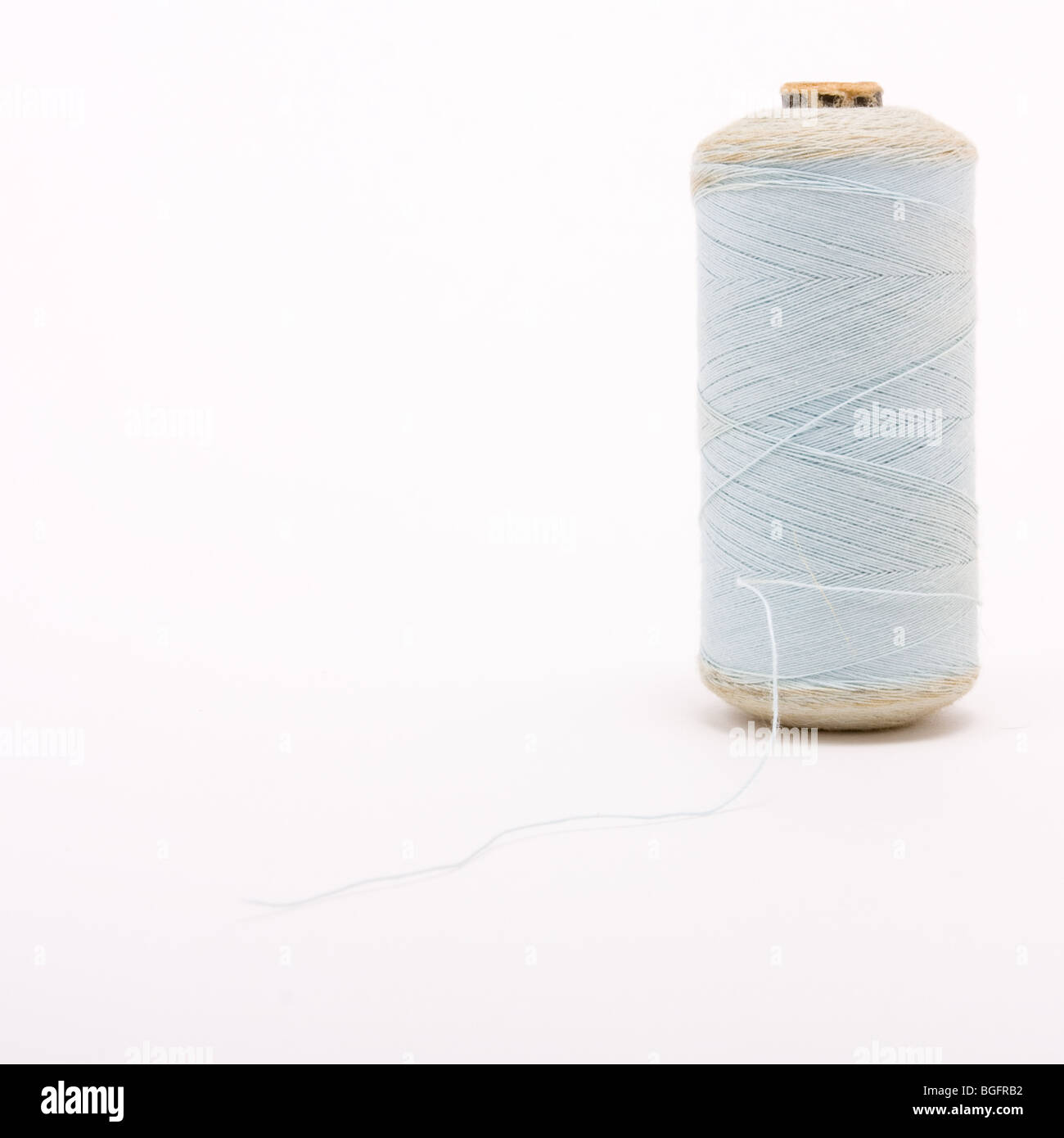 Light blue Cotton thread on bobbin from low perspective against white ...