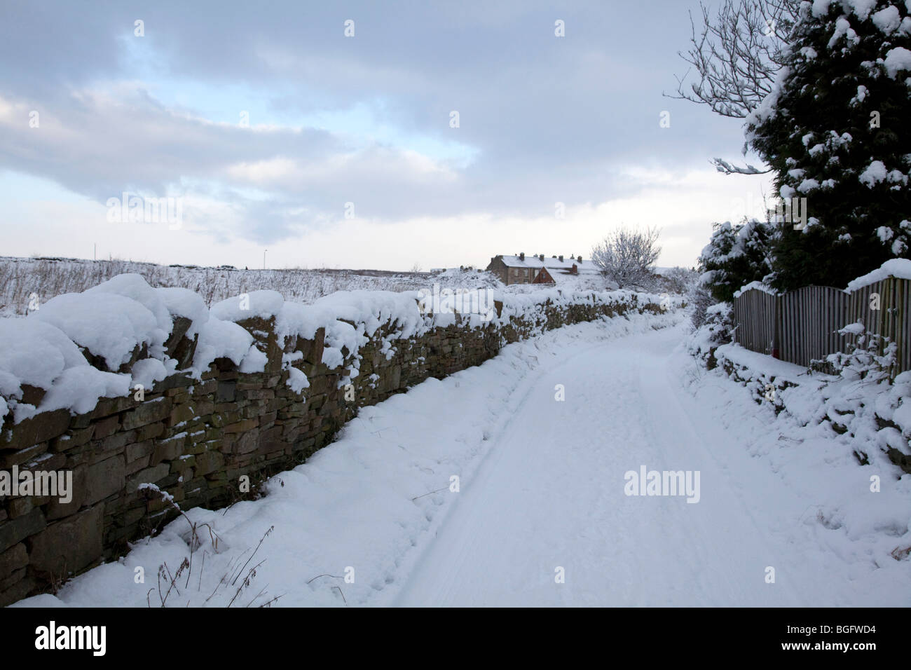 Snowy Country Lane in Yorkshire U.K. in mid winter with houses in the ...