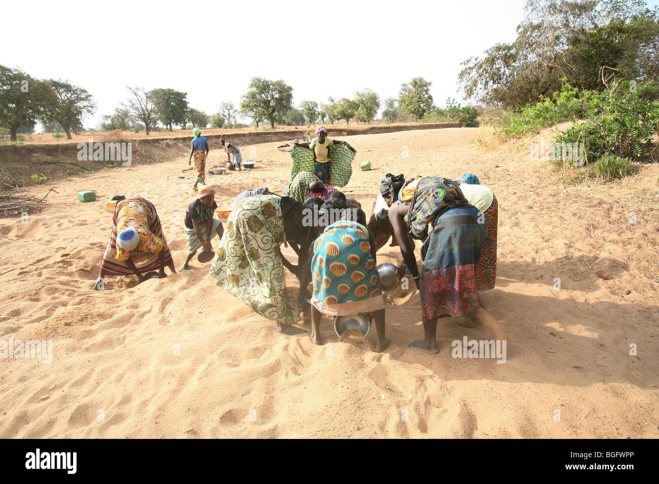 Women digging for water from a dry river bed in rural Burkina Faso ...