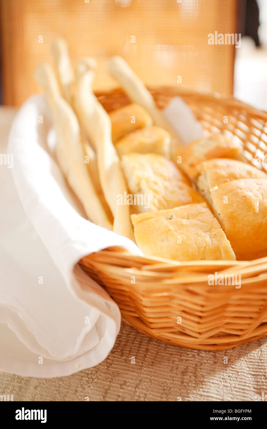 A variety of fresh Italian breads in a wicker basket, draped with a ...