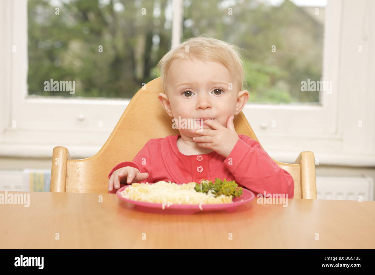 toddler at table ready to eat meal licking finger Stock Photo - Alamy