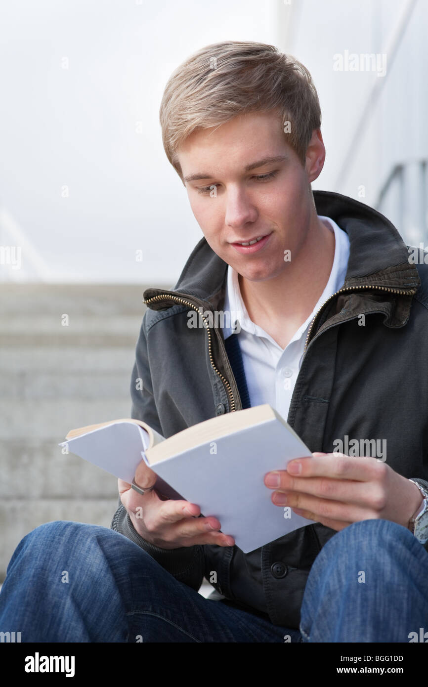 Young cheerful handsome guy reading a book with blank cover Stock Photo ...