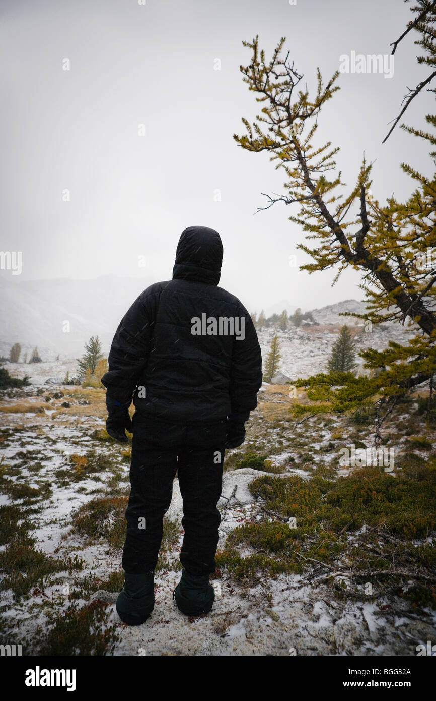 A person all dressed in black winter clothes looking out on a alpine ...