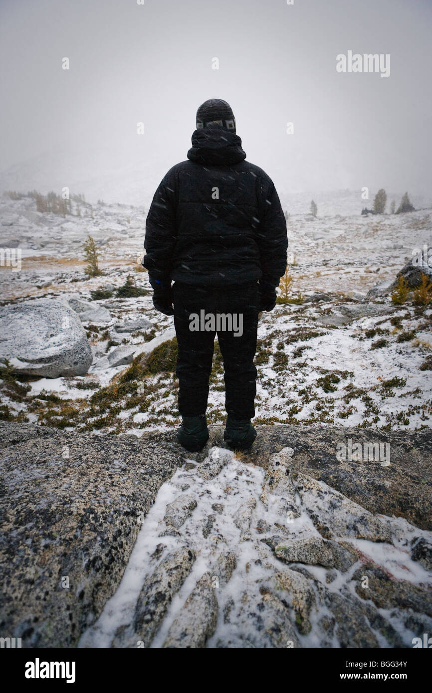 A person all dressed in black winter clothes looking out on a alpine ...