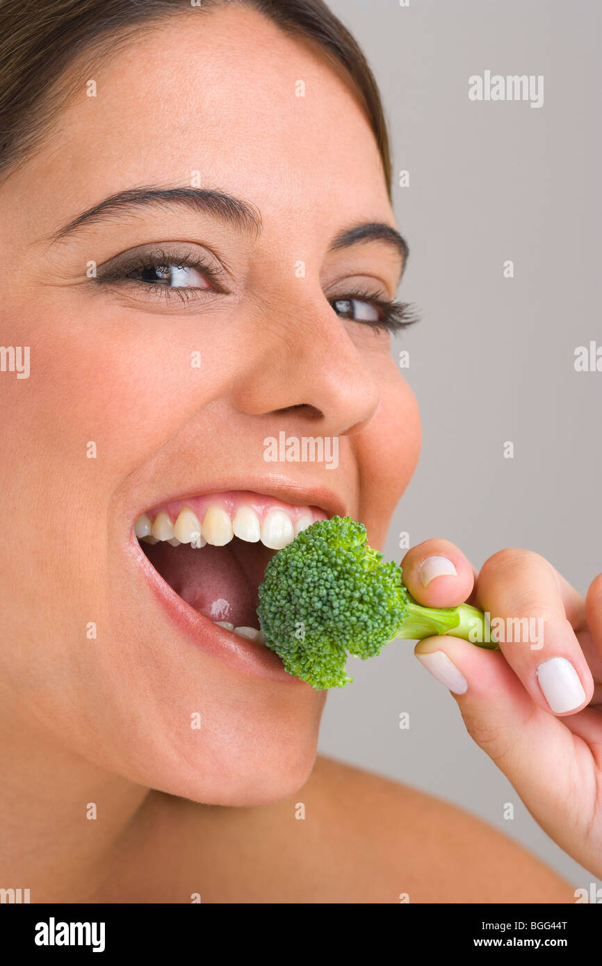 Woman eating a floret of broccoli, Smiling, Portrait Stock Photo - Alamy