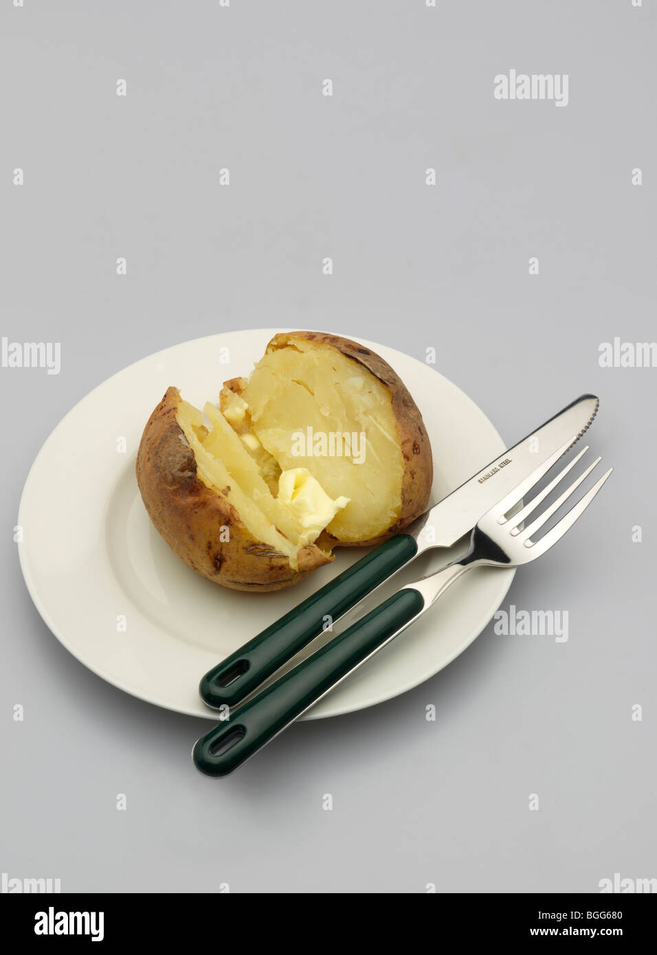 Baked potato on a white plate with a knife and fork Stock Photo - Alamy
