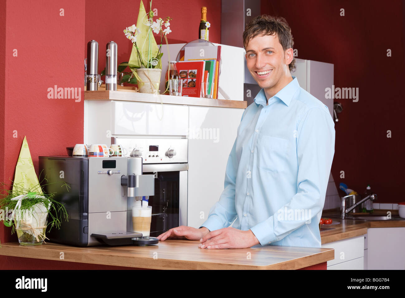 Young man standing in the kitchen beside a coffee machine Stock Photo ...