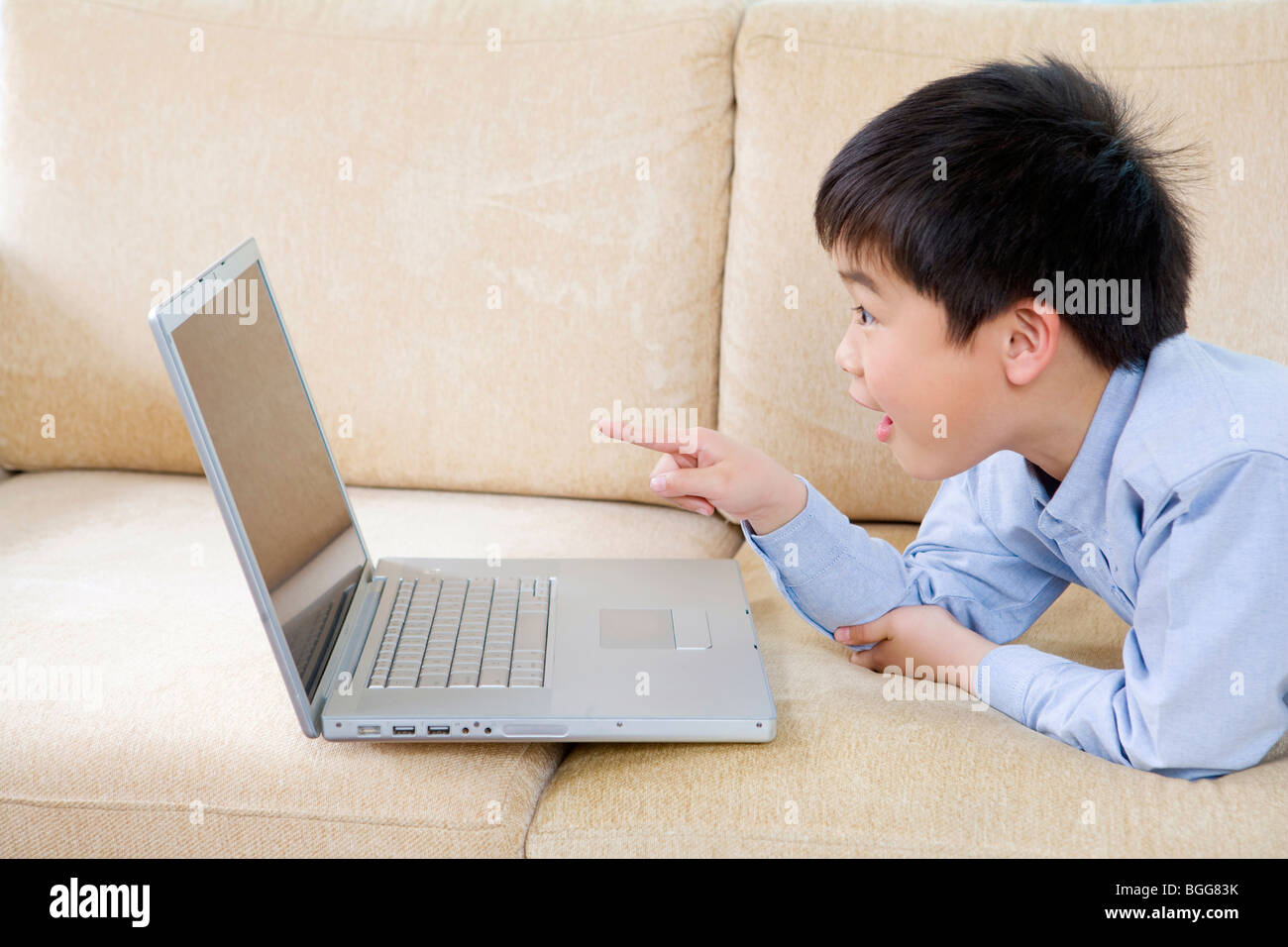 Young boy points at laptop screen on sofa Stock Photo - Alamy