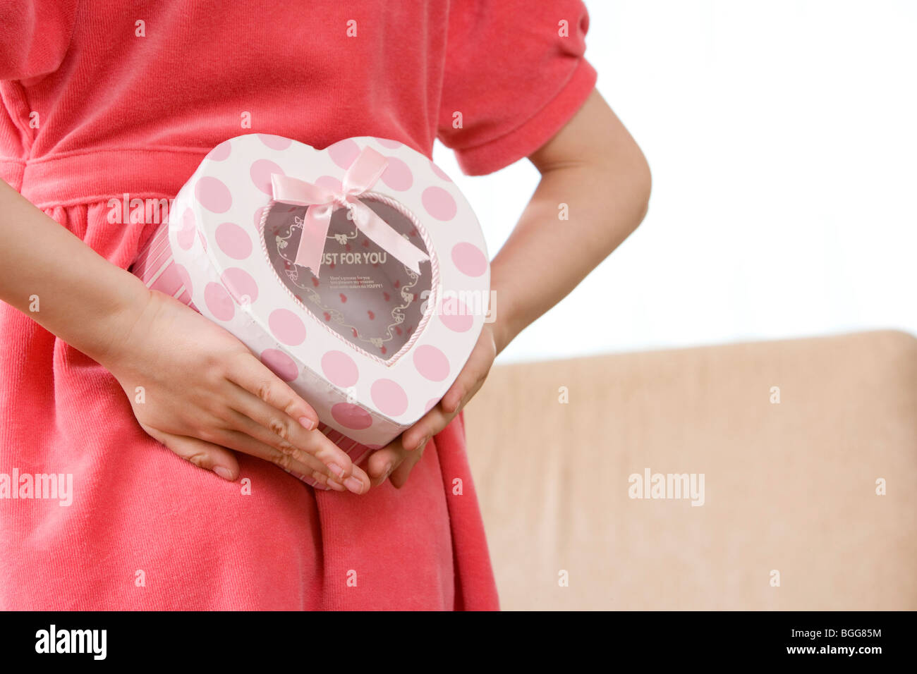 Girl holds heart-shaped box behind her back Stock Photo - Alamy