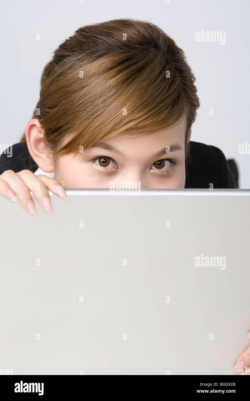 Young businesswoman peeking from laptop behind Stock Photo - Alamy