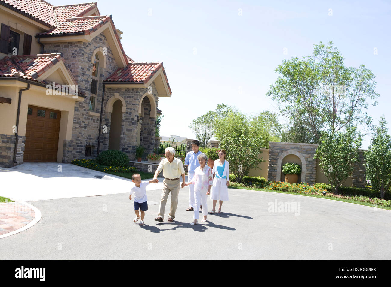 Three generation family walking by a house Stock Photo - Alamy