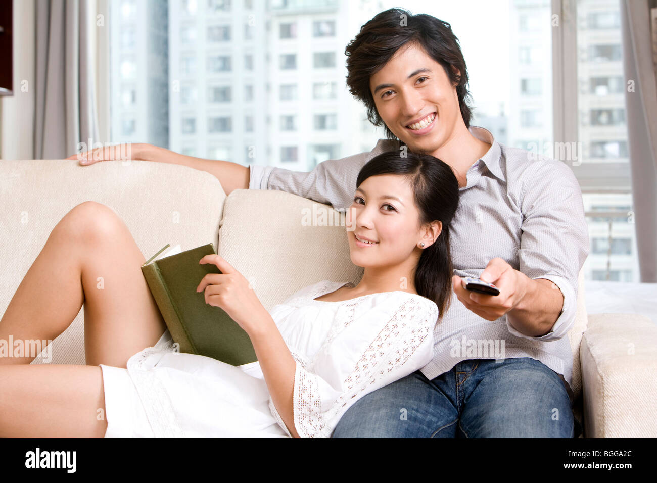 Asian couple cuddling on a sofa Stock Photo - Alamy