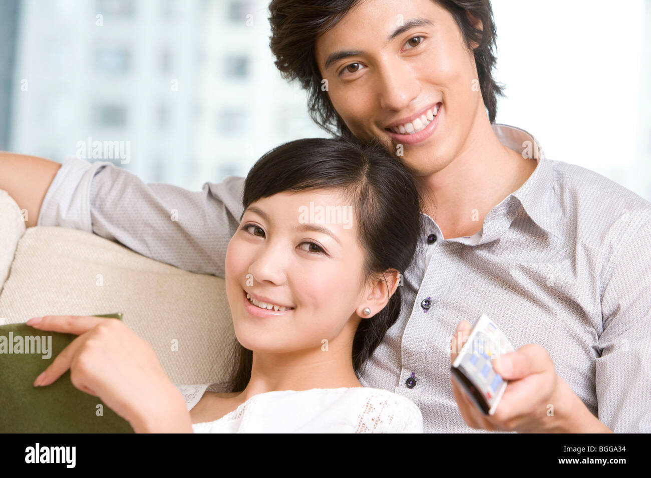 Asian couple cuddling on a sofa Stock Photo - Alamy