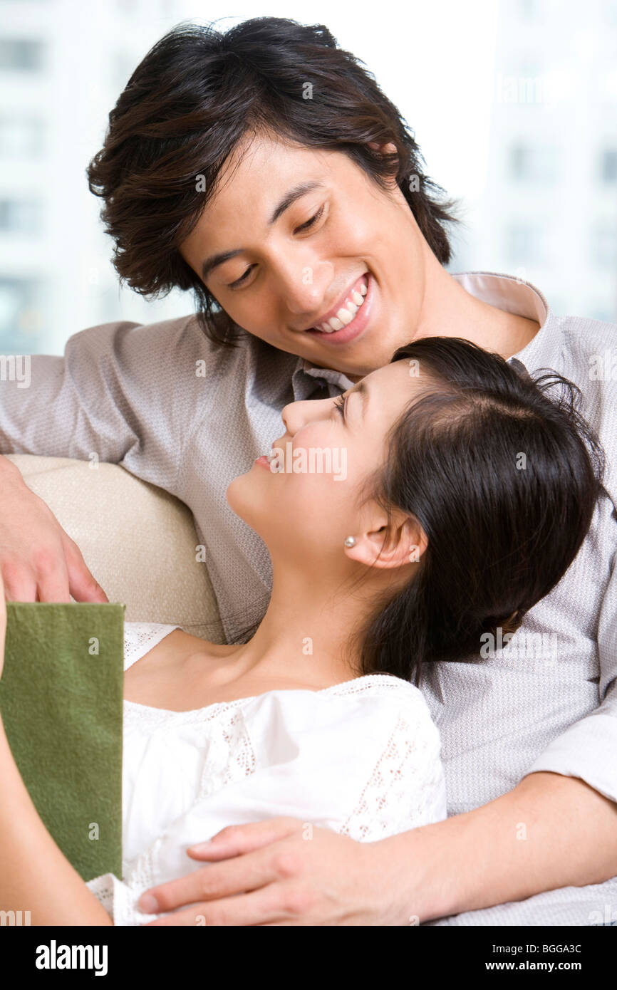 Asian couple cuddling on a sofa Stock Photo - Alamy