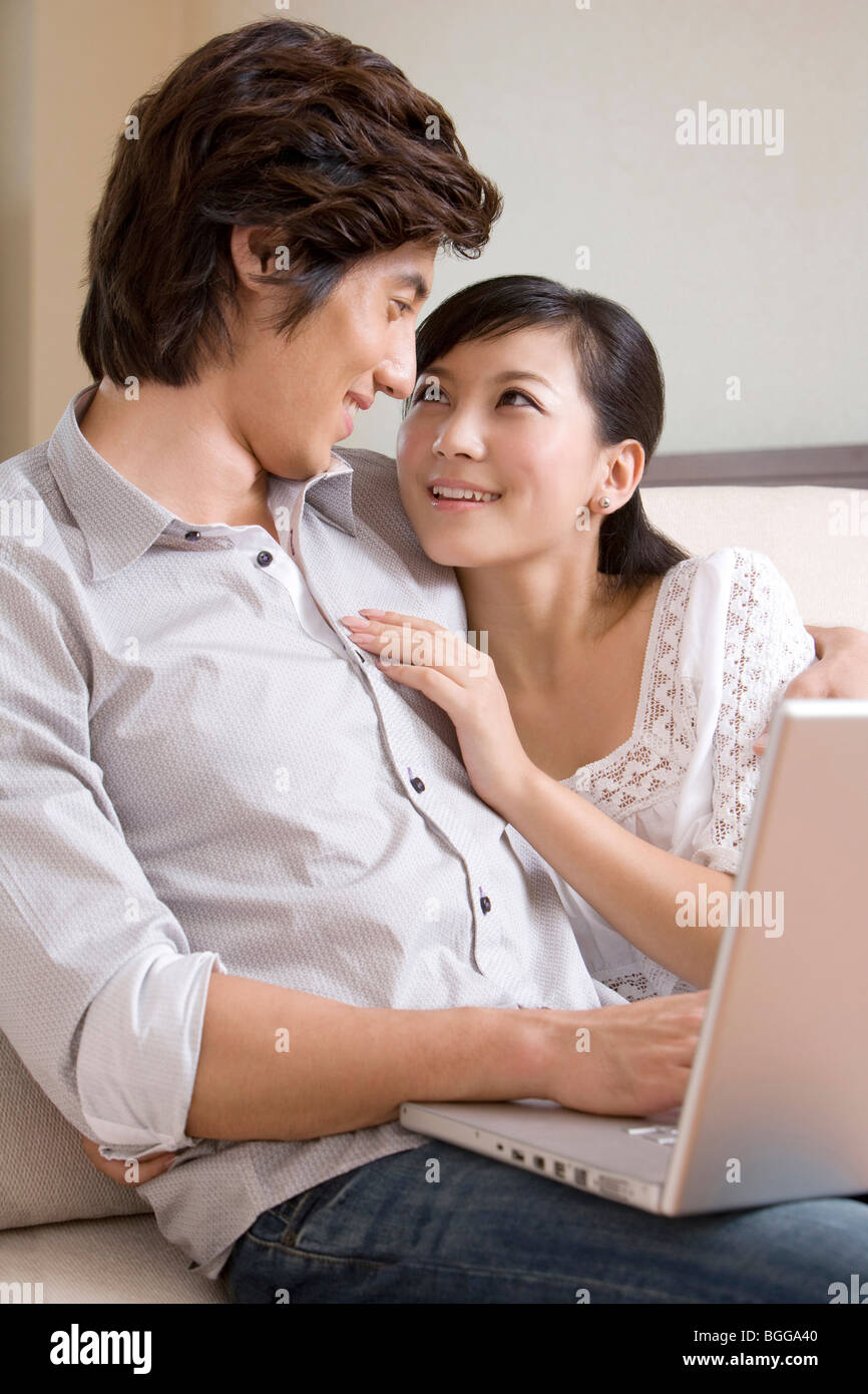 Asian couple cuddling on a sofa Stock Photo - Alamy