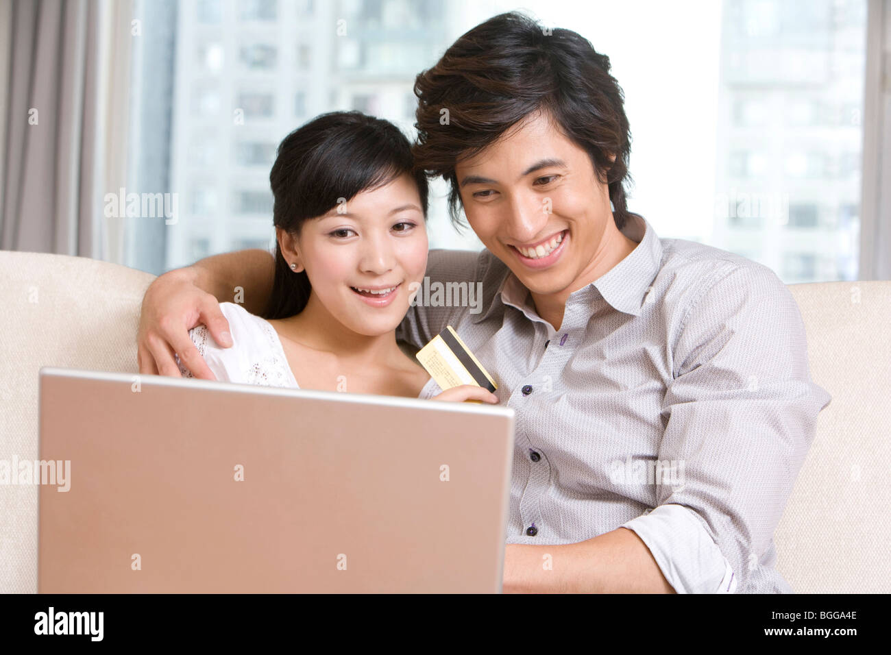 Asian couple cuddling on a sofa Stock Photo - Alamy