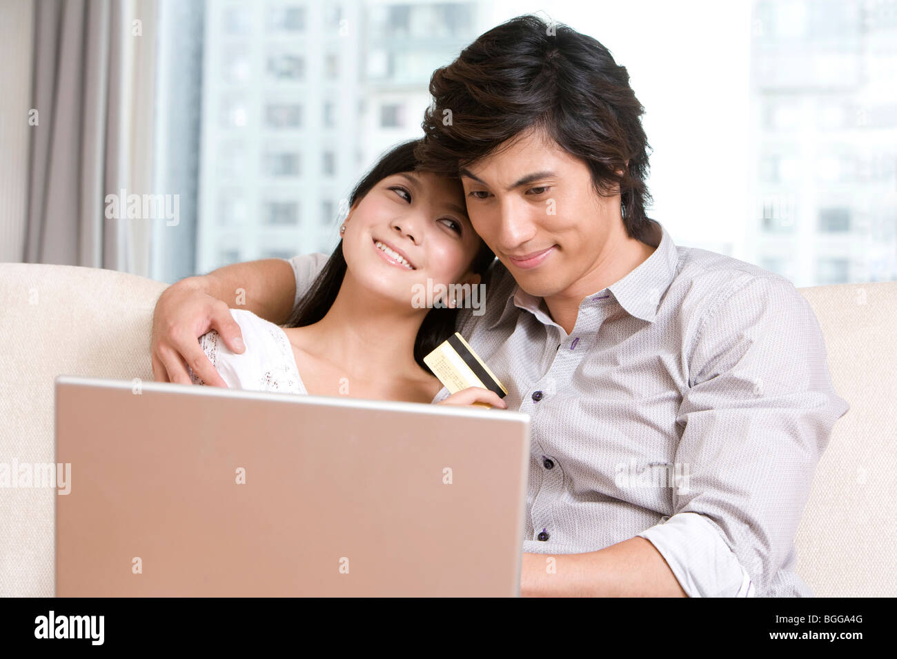 Asian couple cuddling on a sofa Stock Photo - Alamy