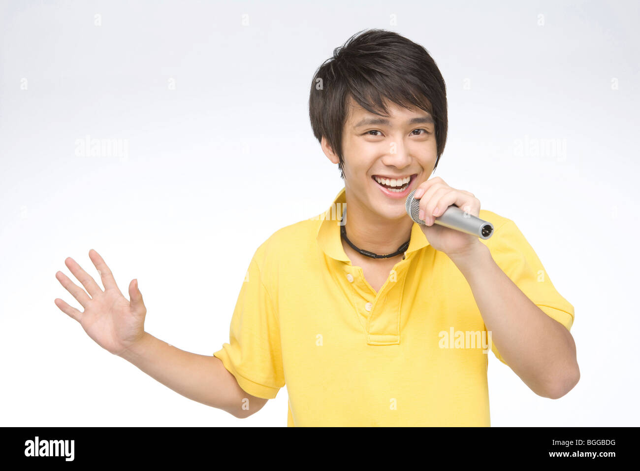 Smiling young man singing songs with microphone Stock Photo - Alamy