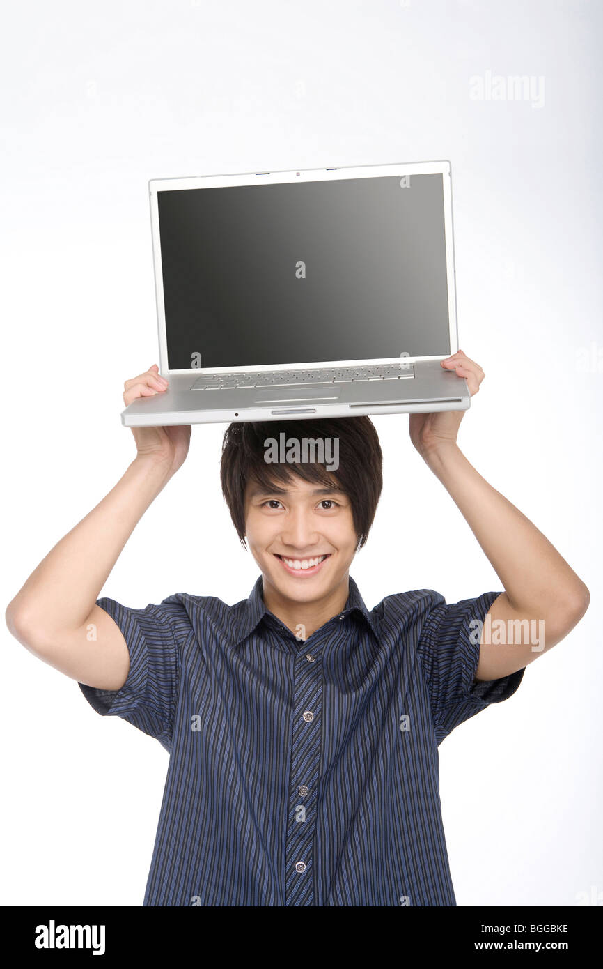 Young man holding laptop on head Stock Photo - Alamy