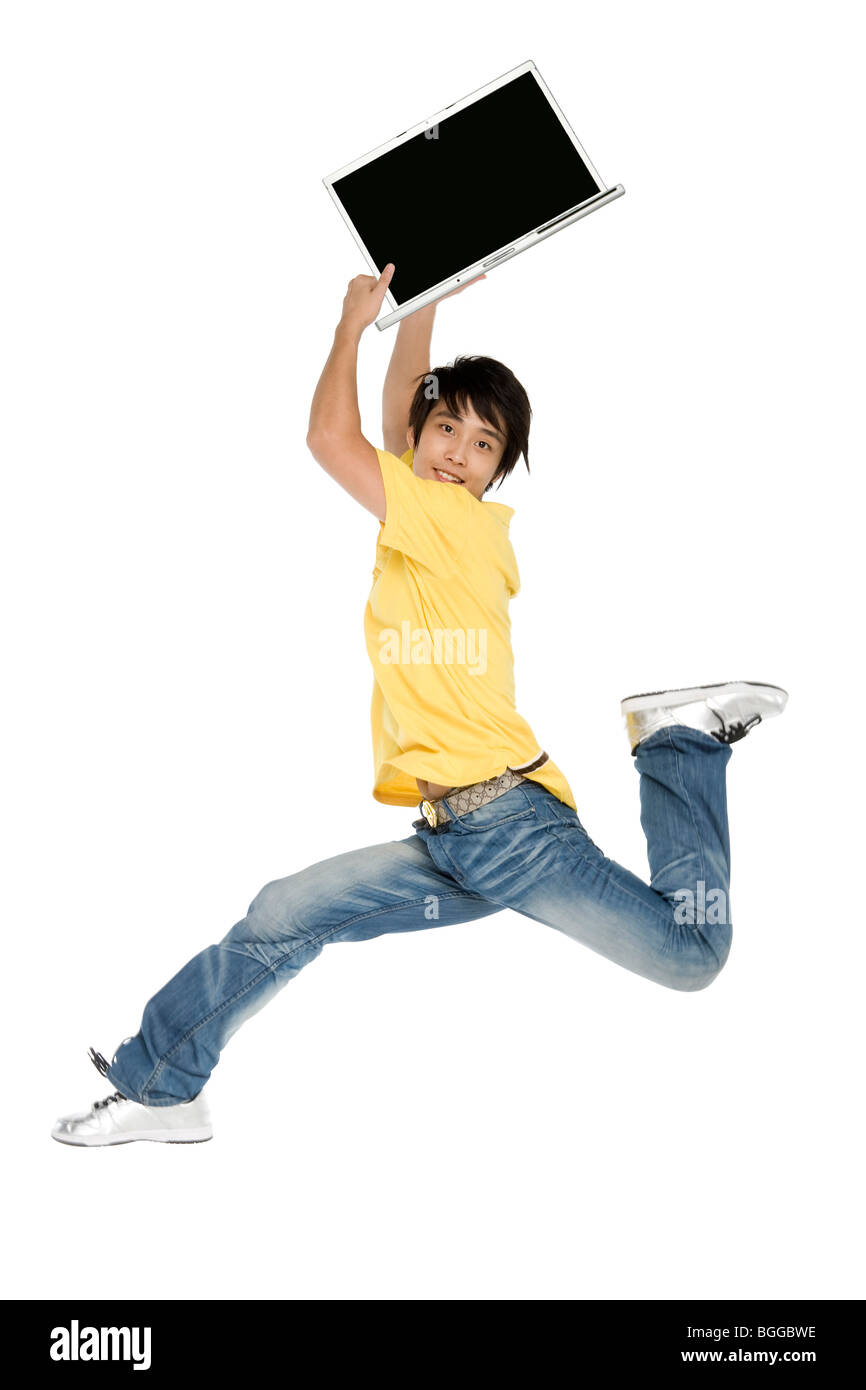 Young man jumping, laptop in hand Stock Photo - Alamy