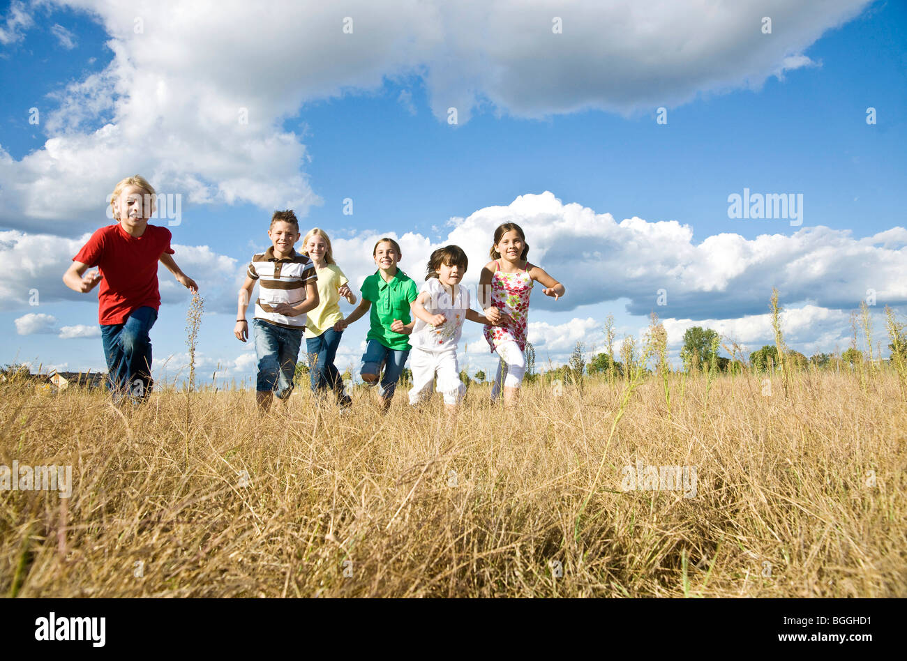 Children running over field, low angle view Stock Photo - Alamy