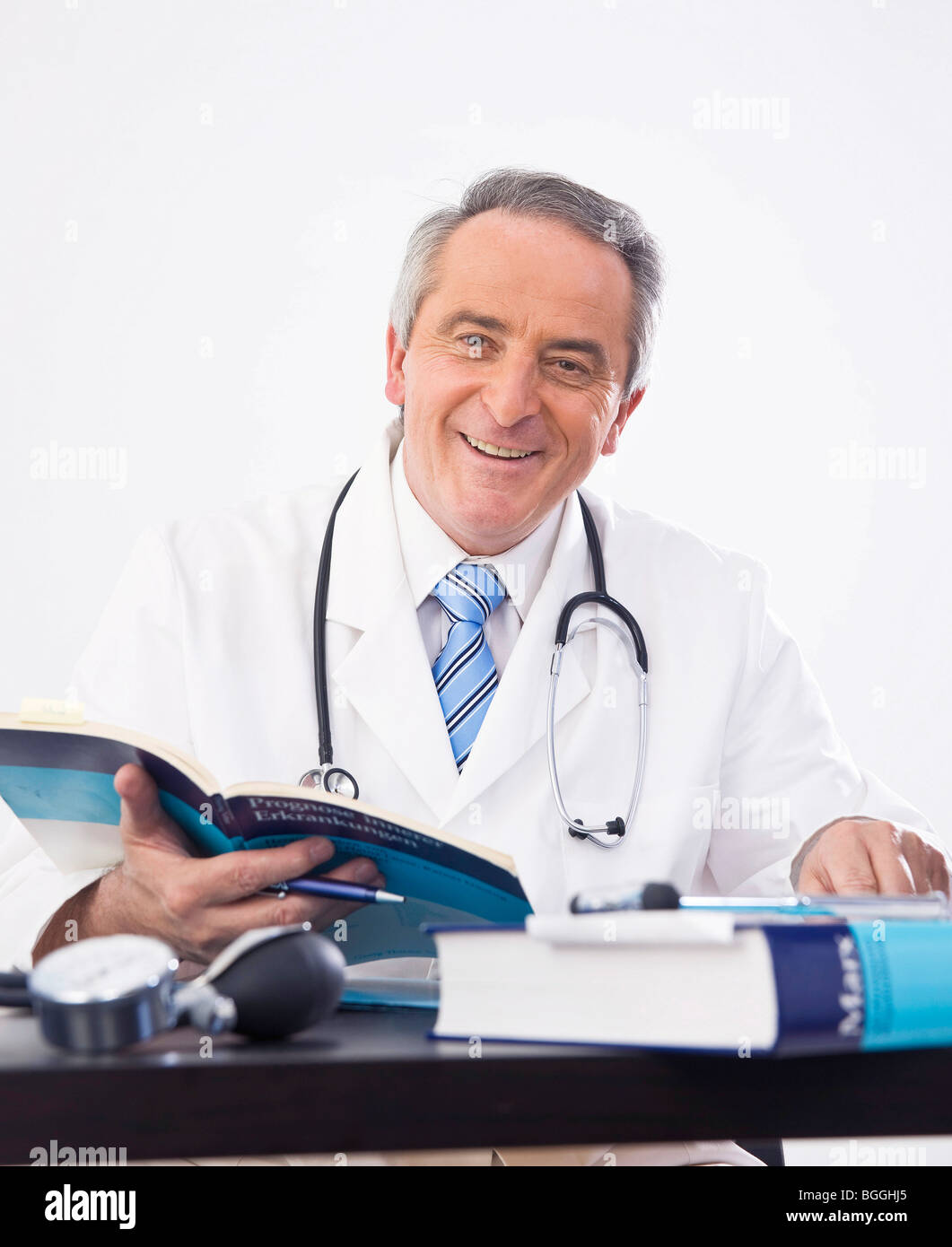 Doctor sitting at a desk, holding a book, portrait Stock Photo - Alamy
