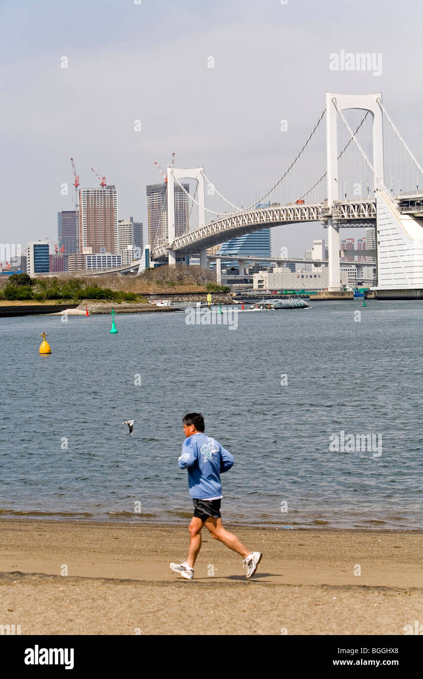 Jogger at the riverbank, Rainbow Bridge and skyline in the background ...