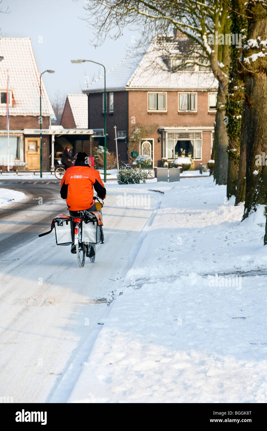 A Dutch postman cycling along a snowy road in the Netherlands Stock ...