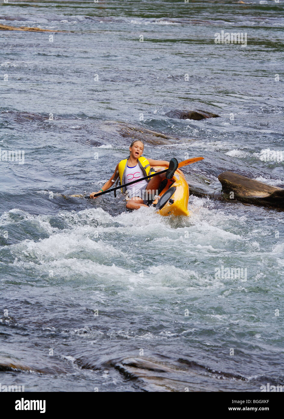 Young girl tipping over paddling through Class I-II rapids in kayak ...