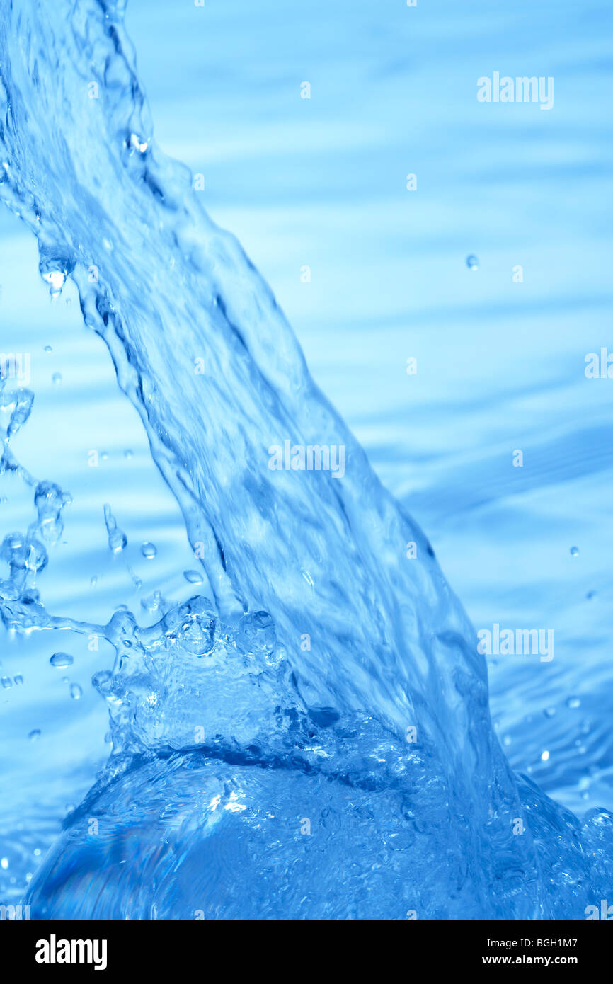 Pouring water close up blue background Stock Photo - Alamy