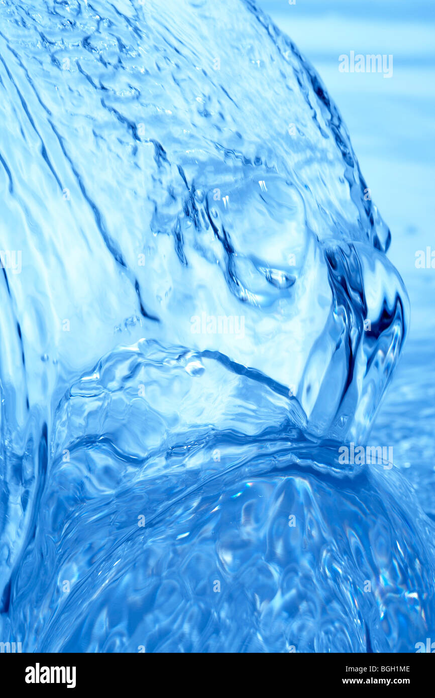 Pouring water close up blue background Stock Photo - Alamy