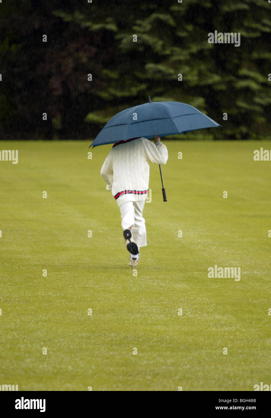 Young cricket player running with an umbrella Stock Photo - Alamy