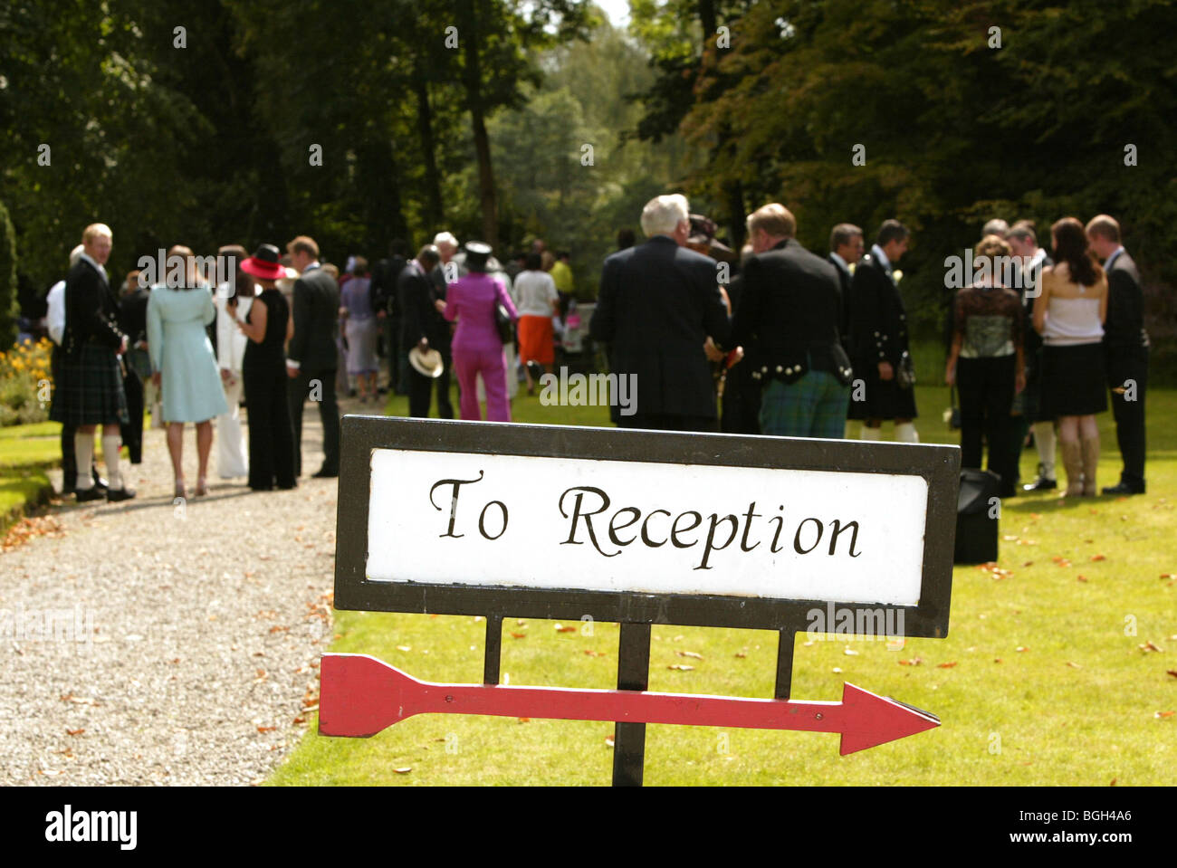 A wedding reception outside in the sunshine with a "To Reception" sign ...