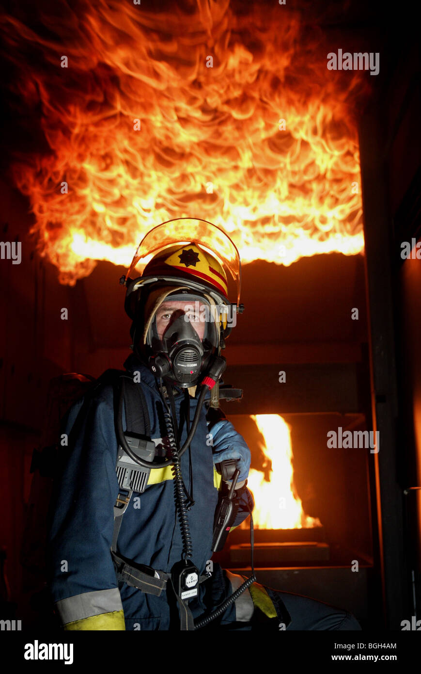 A fireman in a building with flames behind him and on ceiling Stock ...