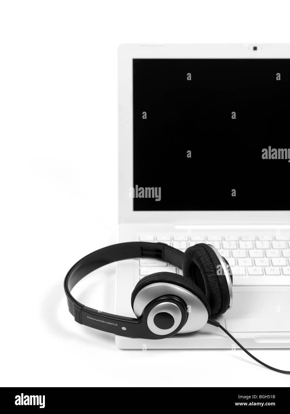 A laptop computer with a set of headphones isolated against a white ...