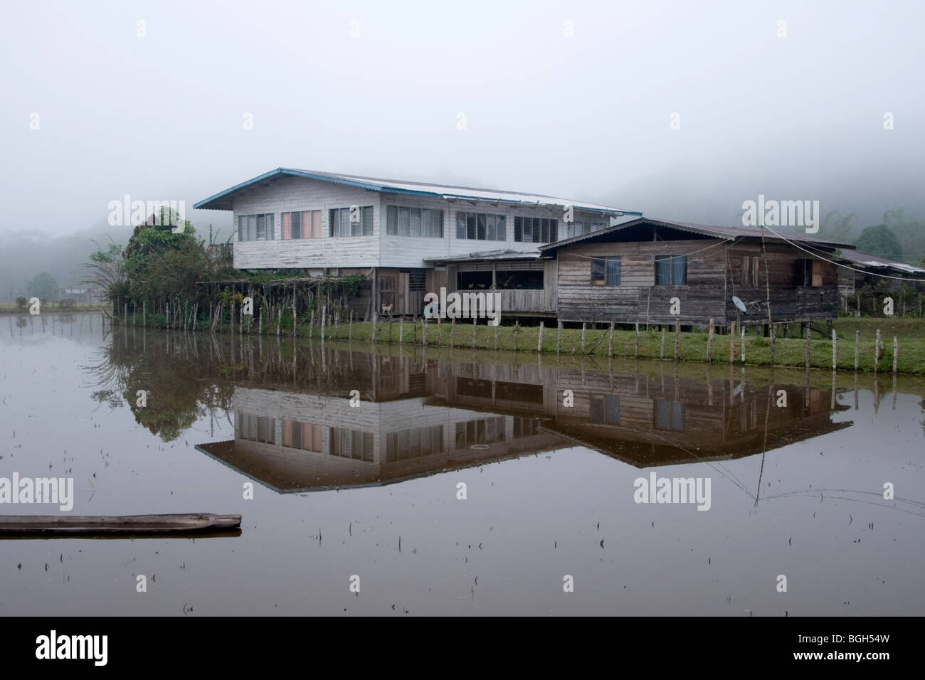A large wooden farmhouse set among paddy fields is shrouded in fog in ...