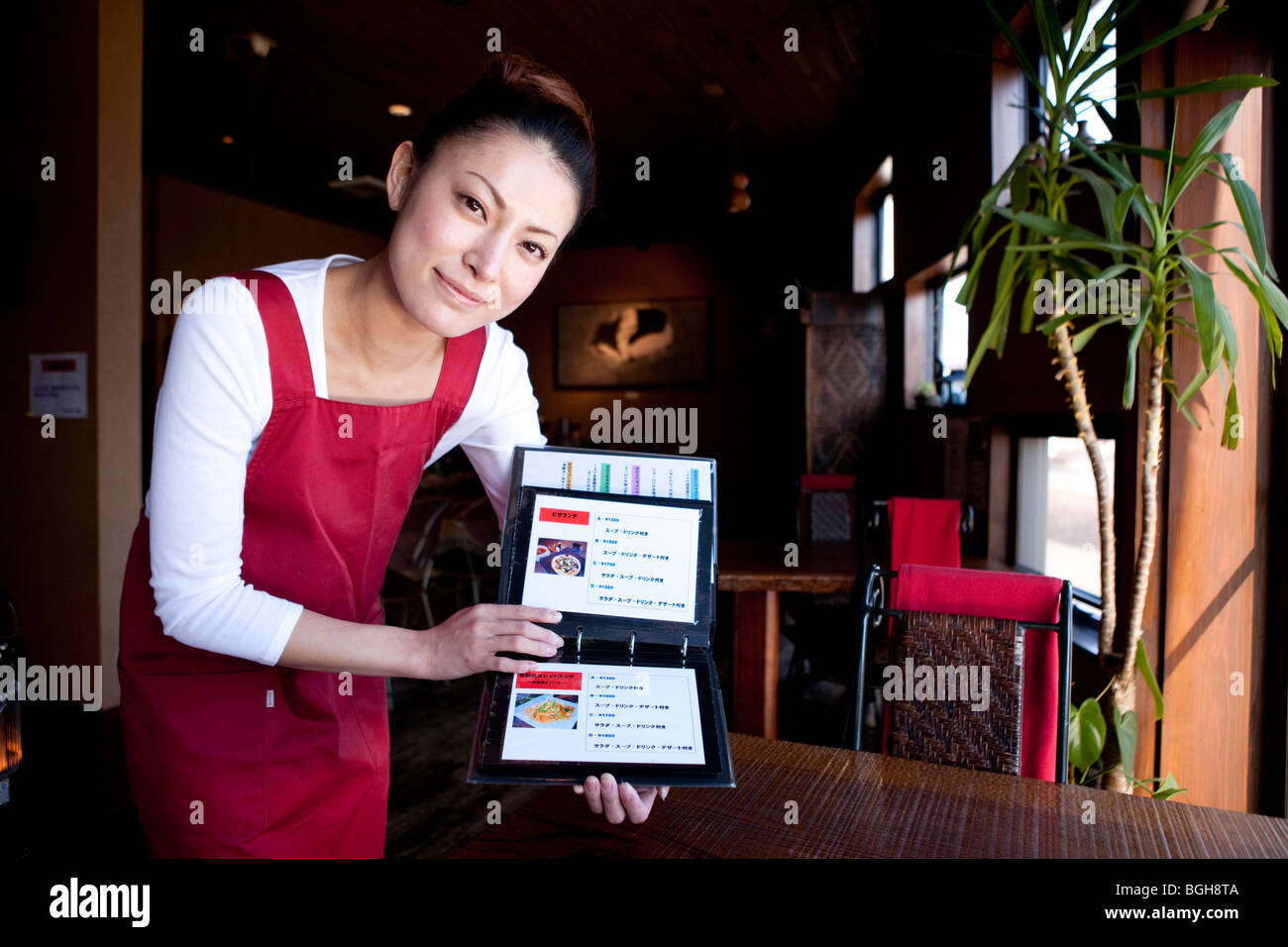 Mid Adult Woman Showing Menu at Table Stock Photo - Alamy