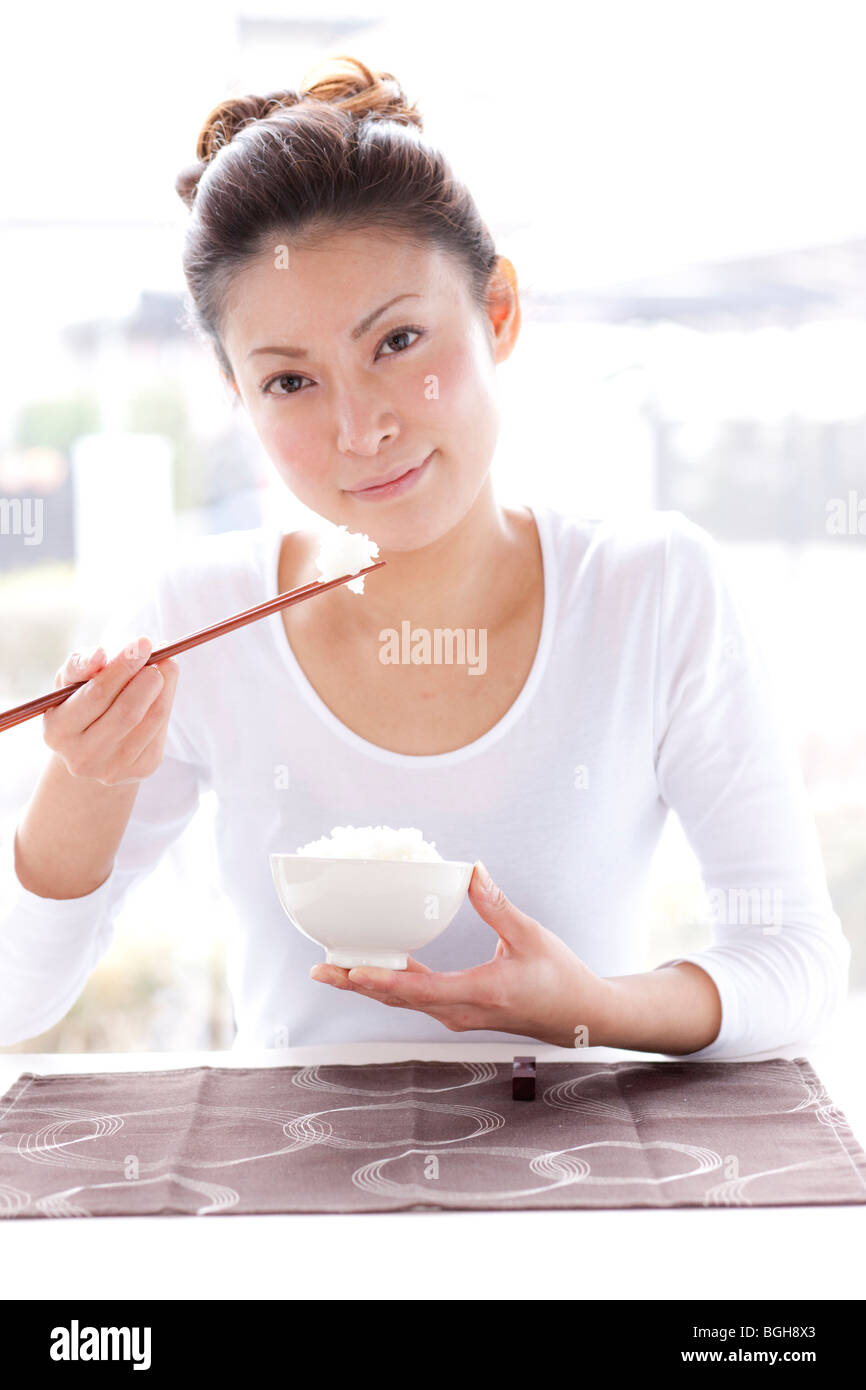 Young Woman at Table Eating Bowl of Rice Stock Photo - Alamy