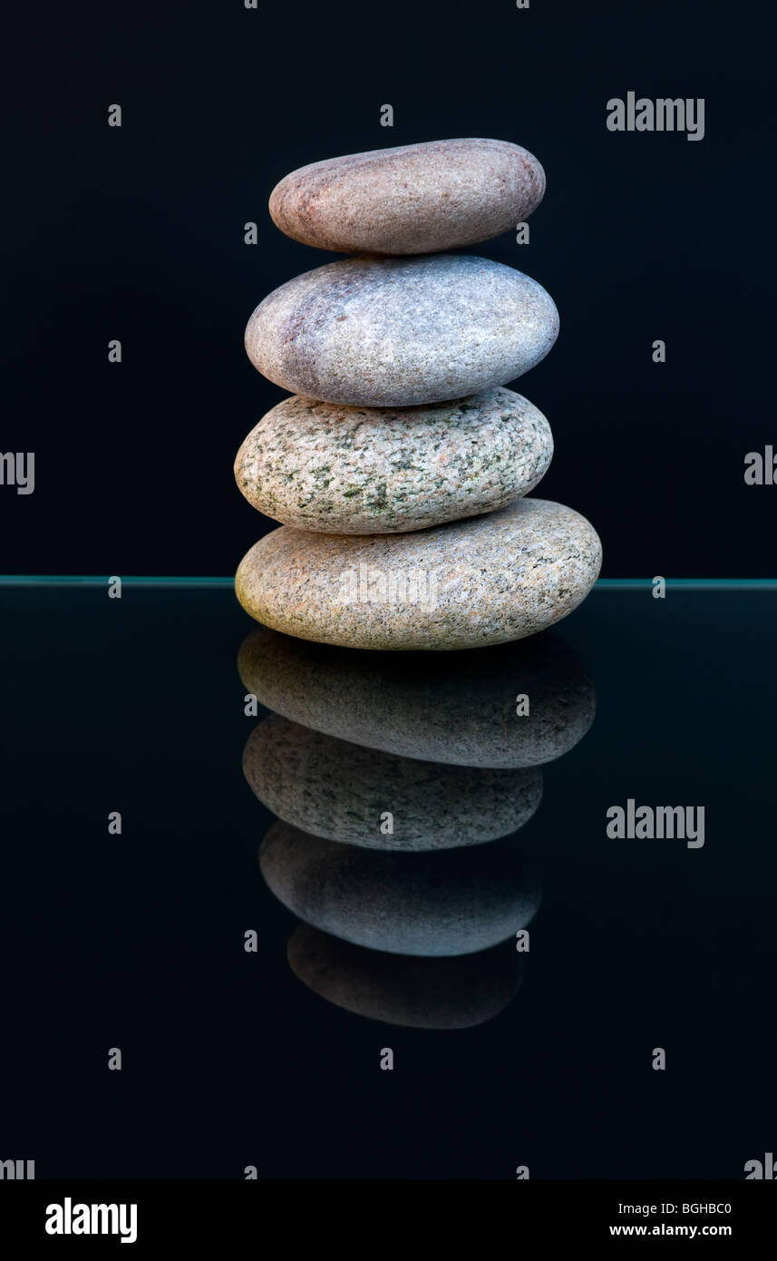 Still life shot of four beach pebbles balanced in a stone pile against ...