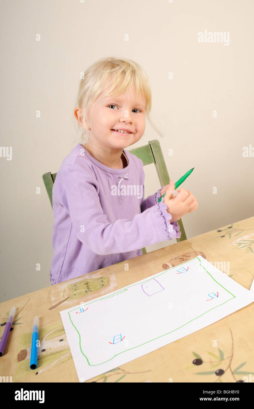 Stock photo of a four year old girl drawing pictures on a piece of ...