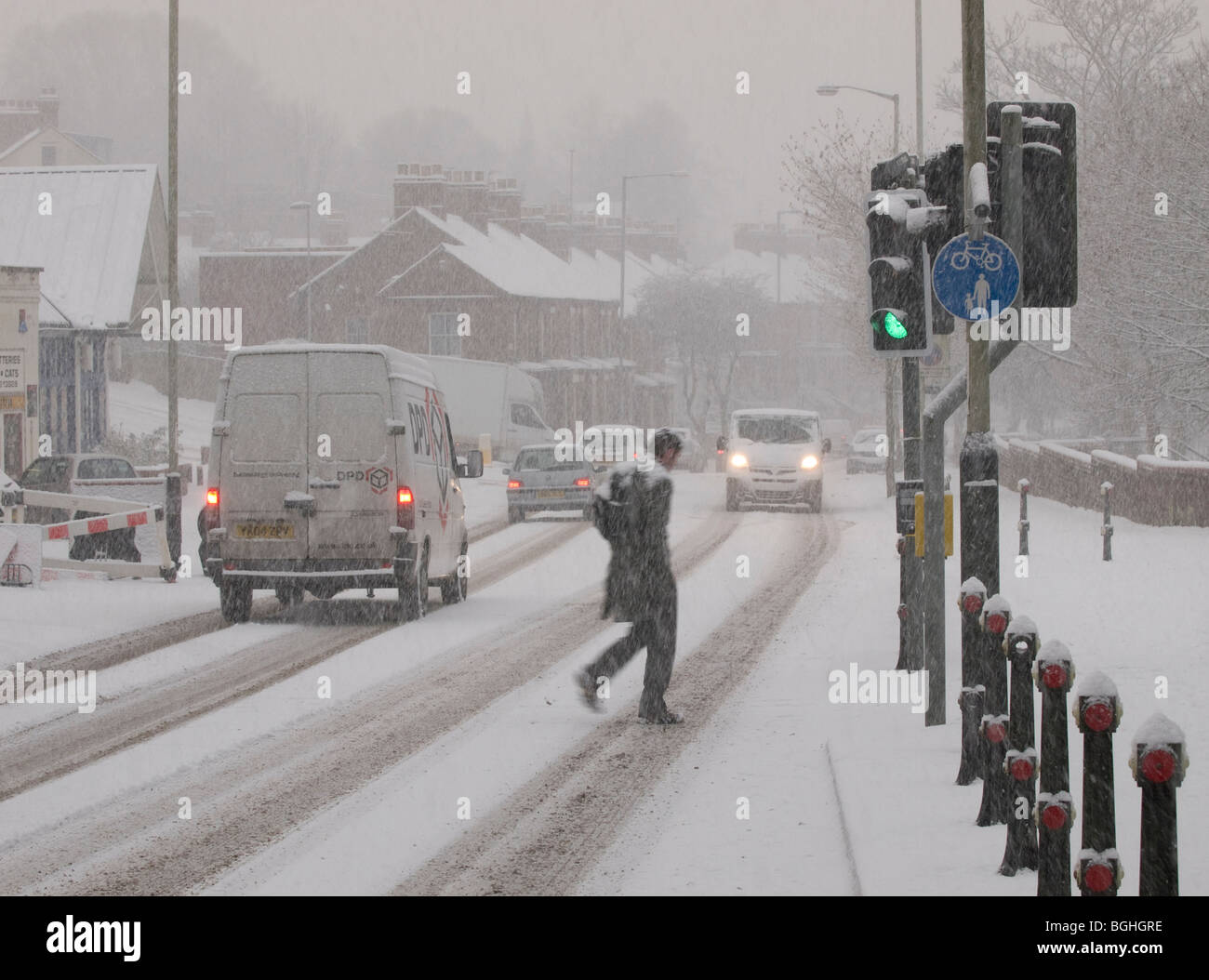 MAN CROSSING ROAD AT ZEBRA PEDESTRIAN WITH TRAFFIC IN THE SNOW ON ...