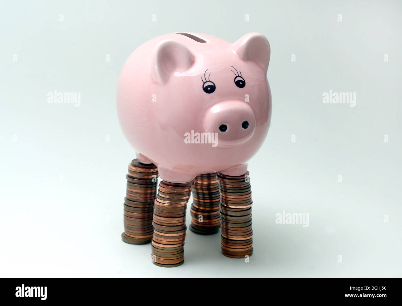 PIGGY BANK,PIGGYBANKS STANDING ON PILES OF BRITISH COINS RE THE ECONOMY ...