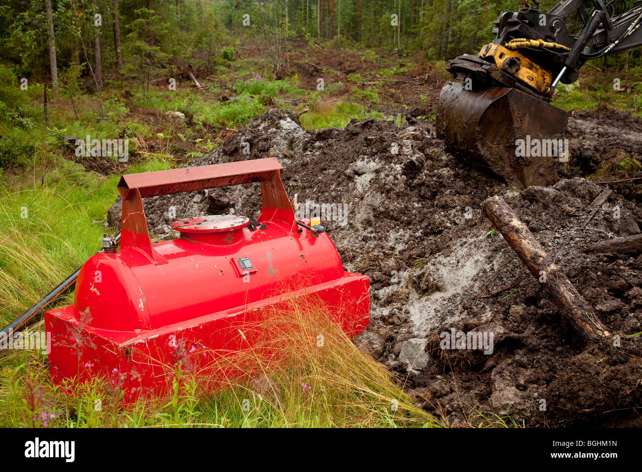 Red movable diesel fuel tank and digger bucket digging muddy ground ...