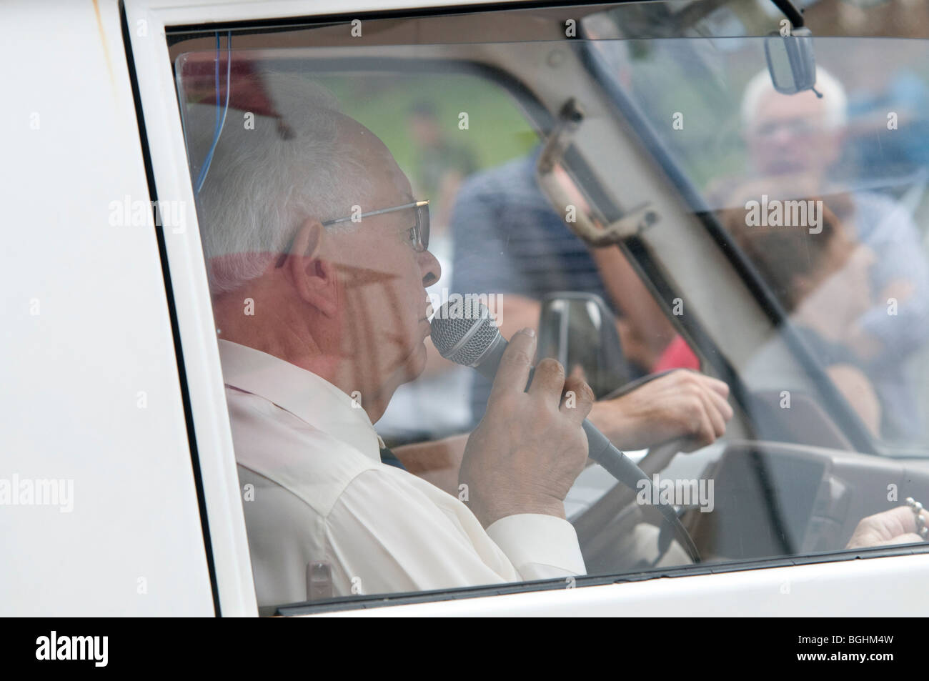 priest talking on the microphone inside a van in a procession (Portugal ...