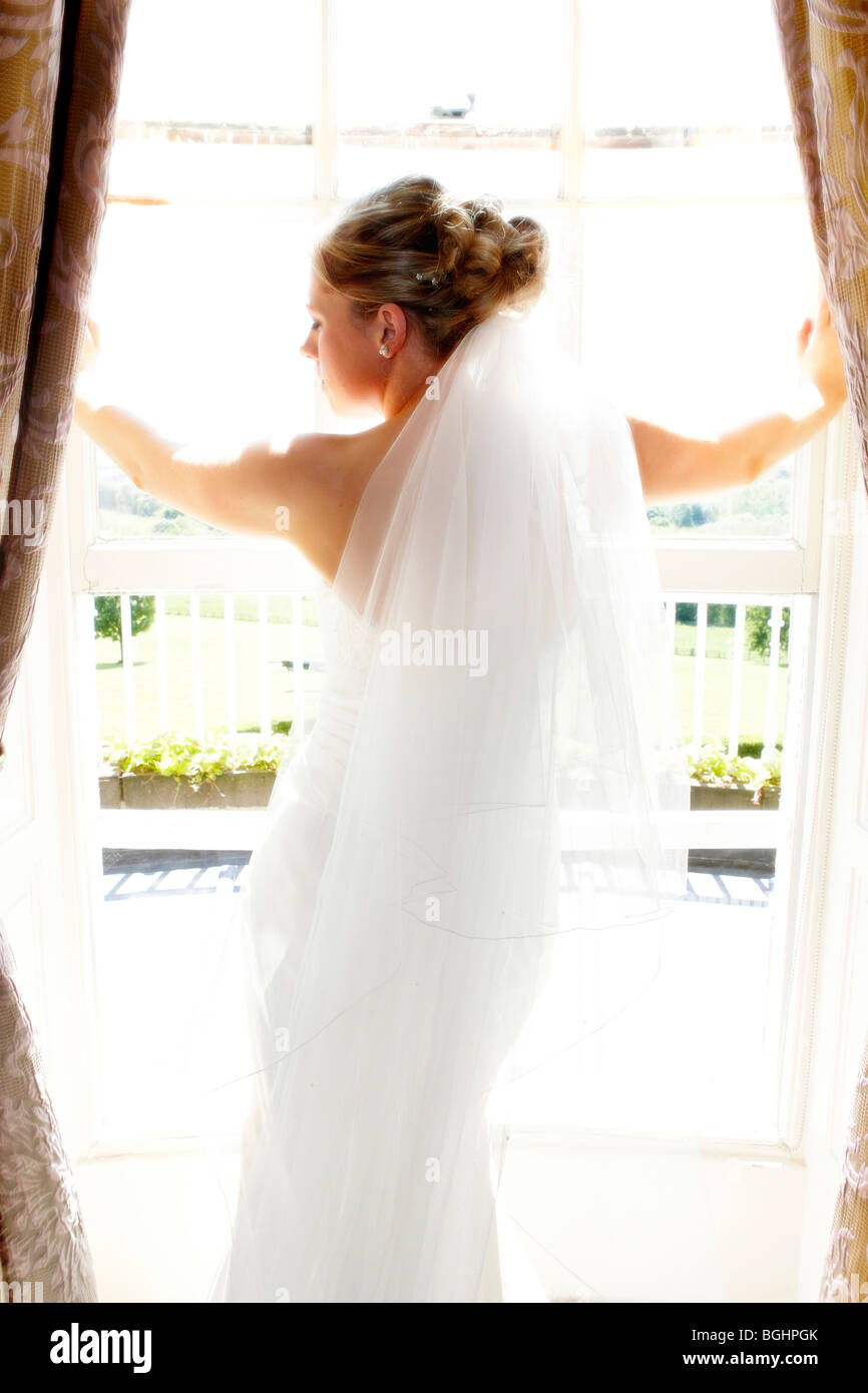 Bride looking out of window Stock Photo - Alamy