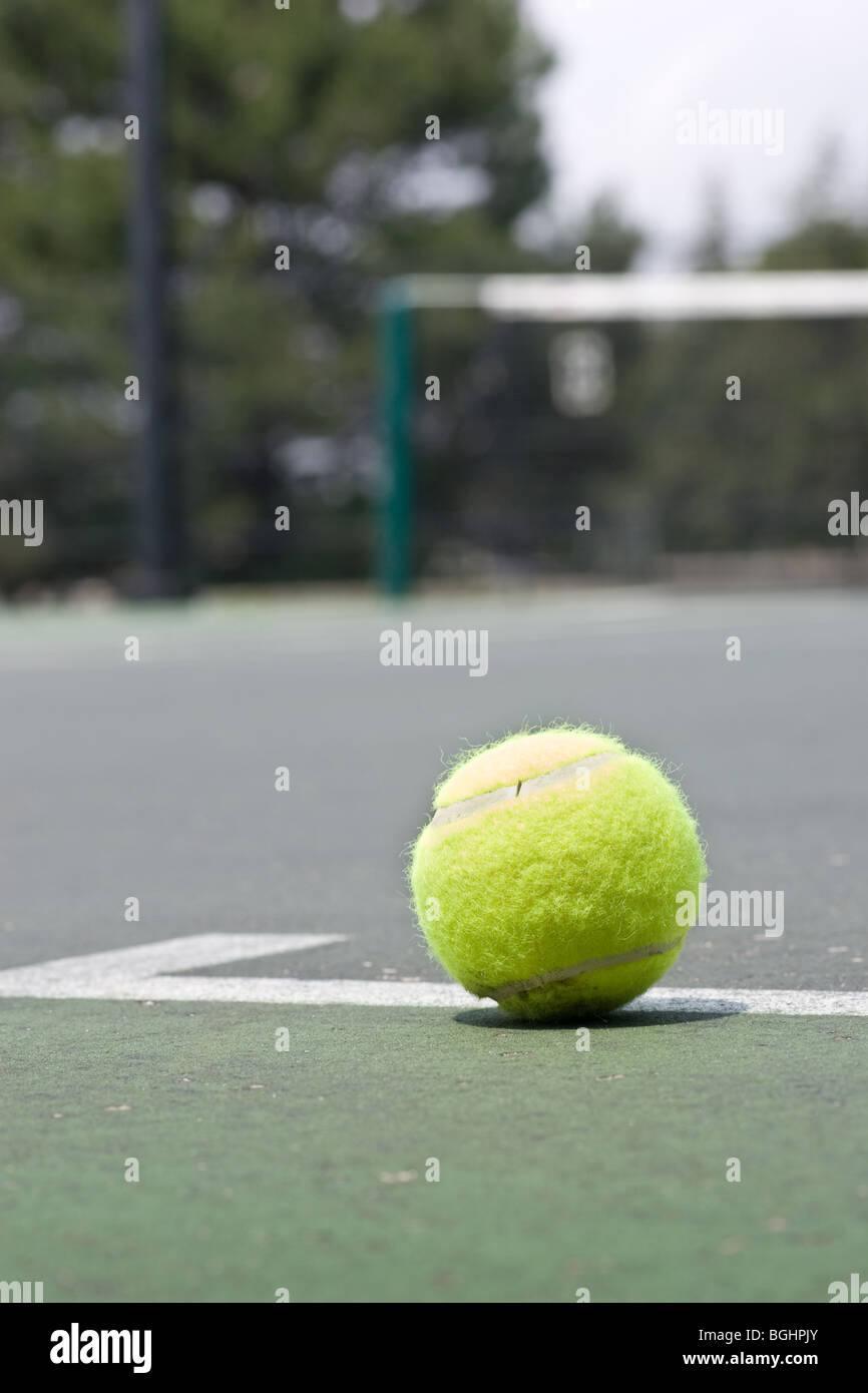 A closeup of a yellow tennis ball just outside of the base line on an ...